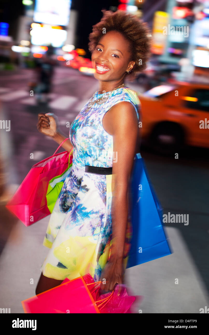Woman carrying shopping bags on city street Stock Photo - Alamy