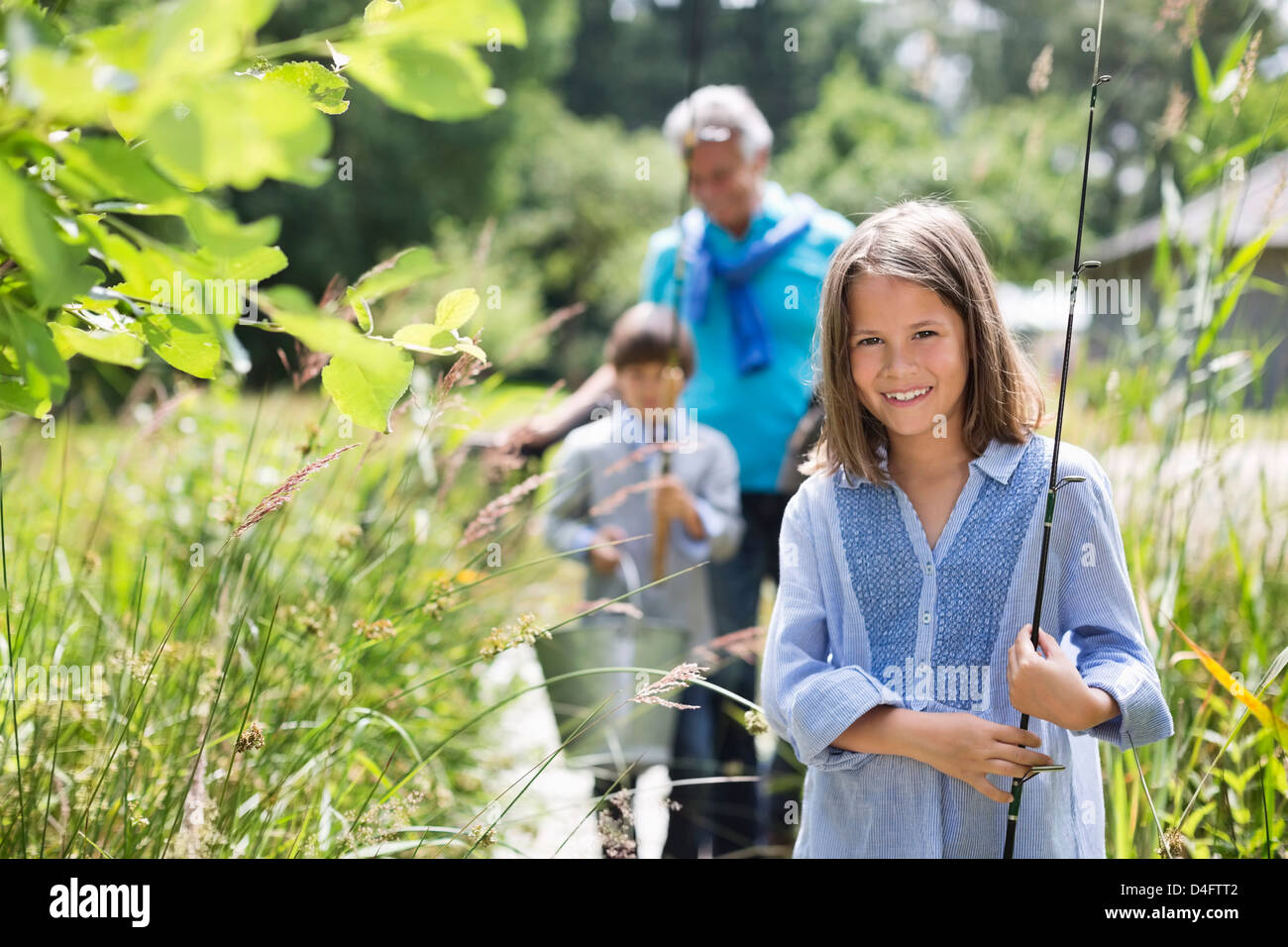 Girl carrying fishing rod in tall grass Stock Photo - Alamy