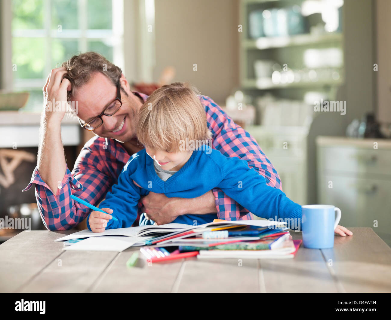 Father and son doing homework at kitchen table Stock Photo - Alamy