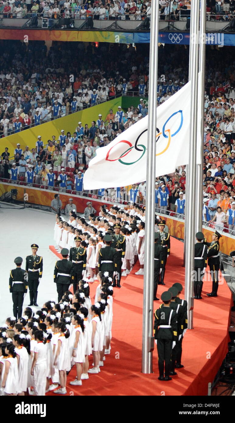 The Olympic flag is being lowered to be folded by honour guard during ...