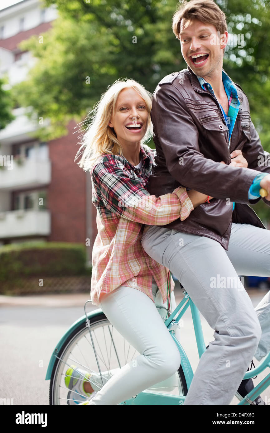 Couple riding bicycle together on city street Stock Photo - Alamy