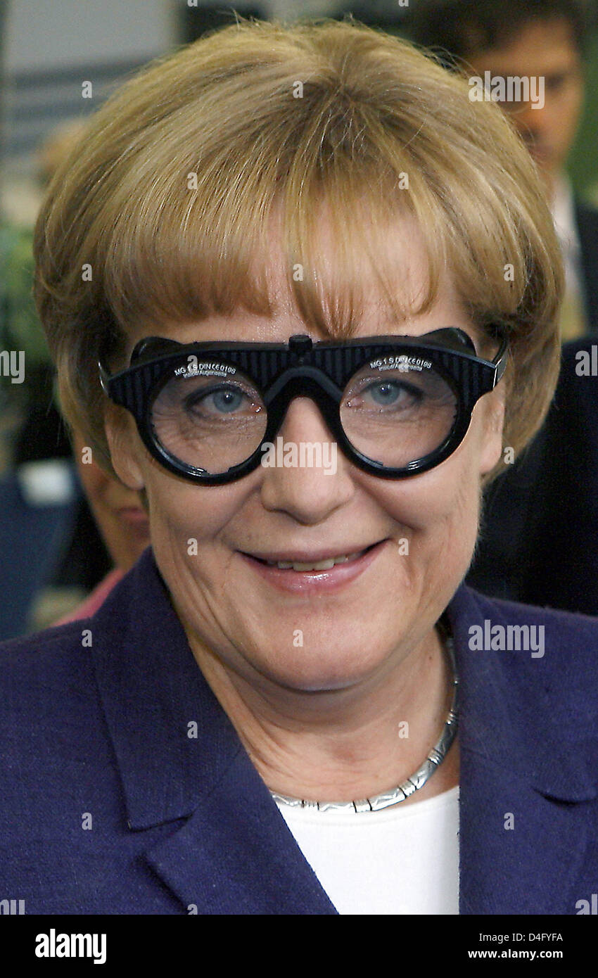 German Chancellor Angela Merkel puts on a pair of goggles as she stands ...