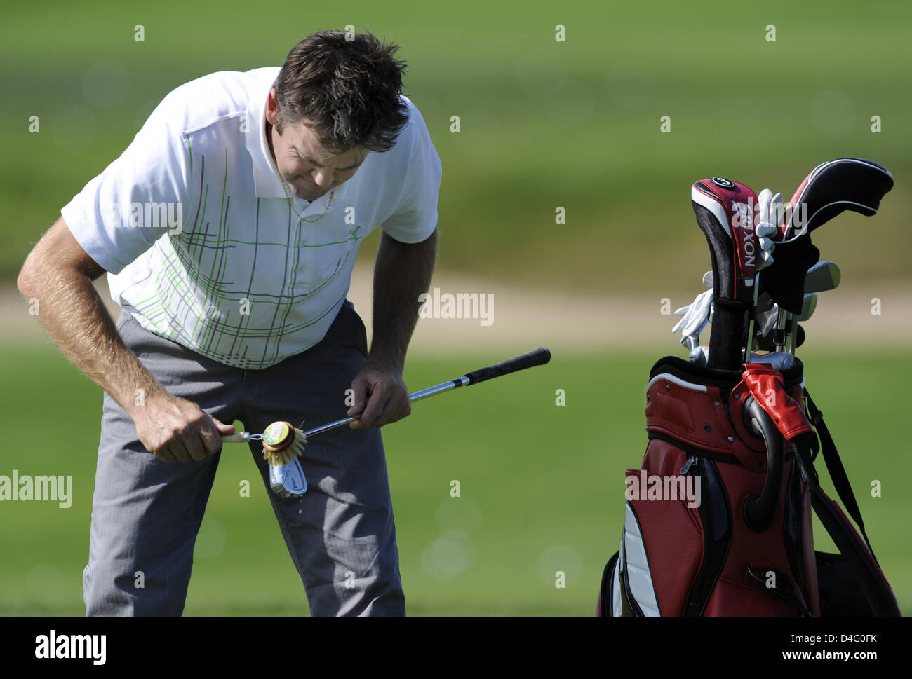 New Zealand golfer Mark Brown cleans his silver golfclub at driving ...