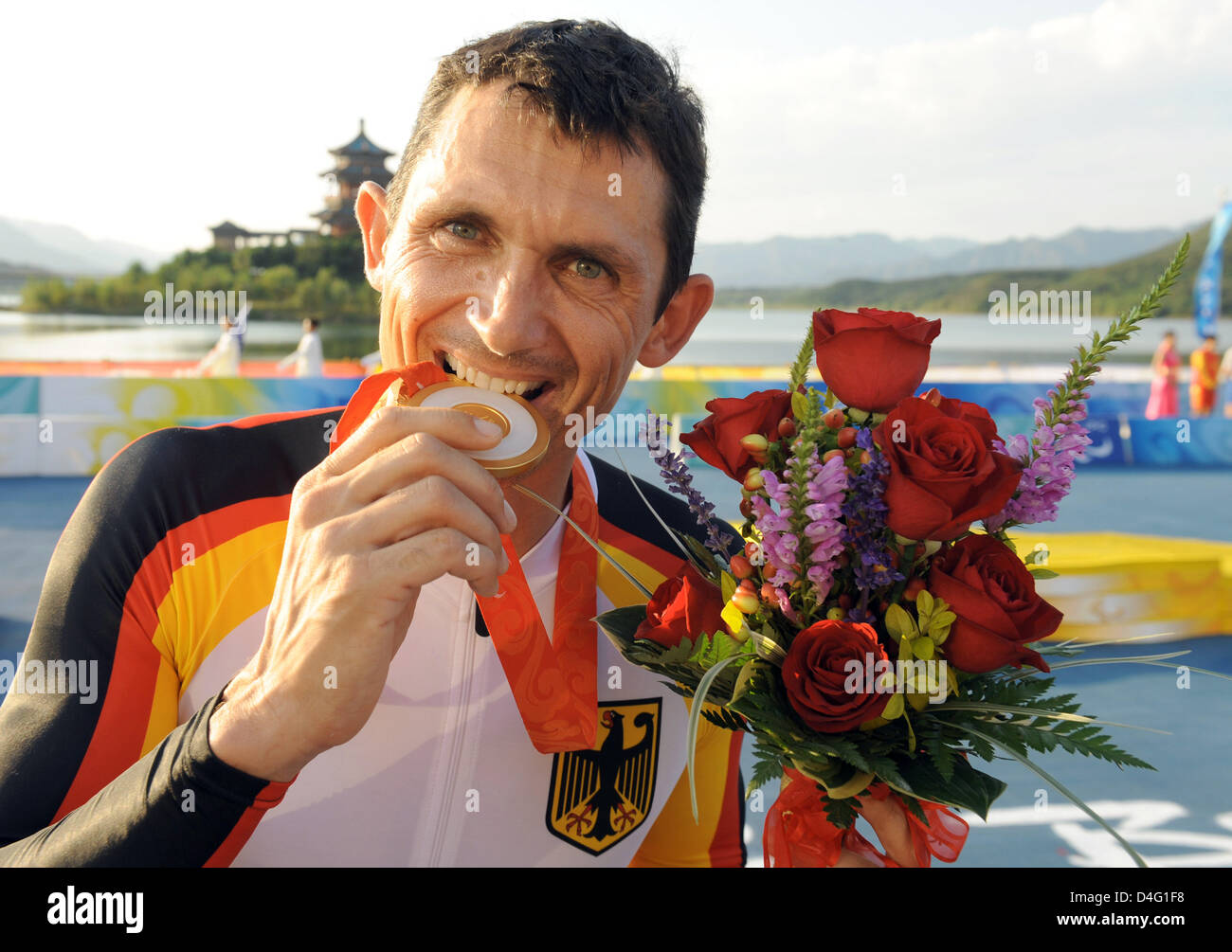 Bronze medal winner Fabio Triboli (R) from Italy bites into the gold ...