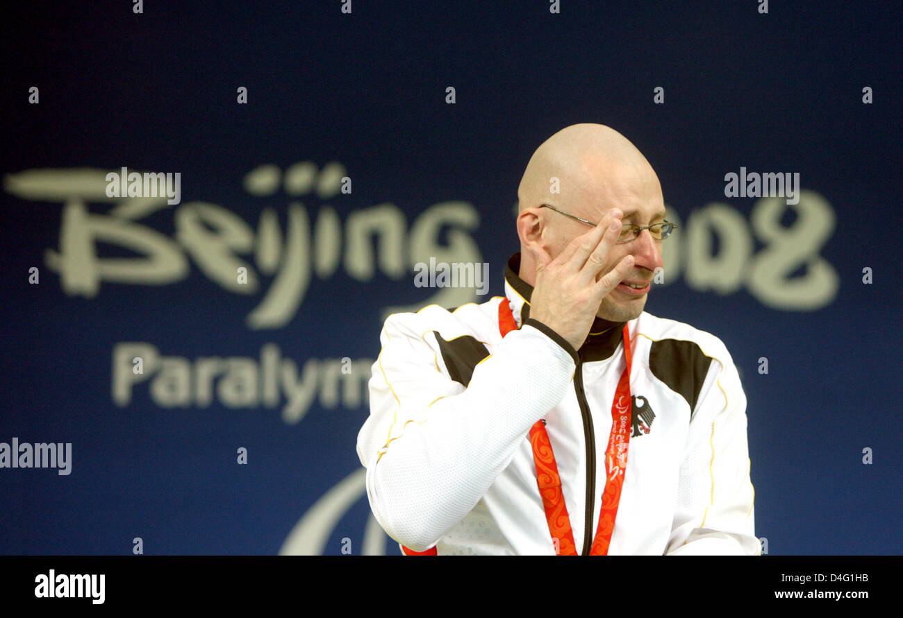 German swimmer Thomas Grimm wipes off a tear during the 100m ...