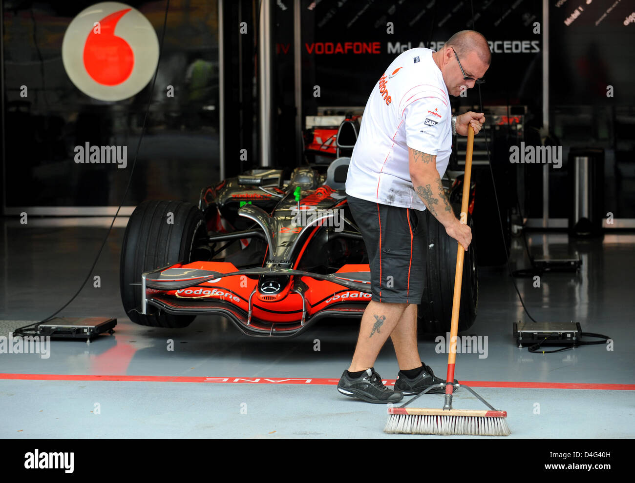 A mechanic of McLaren Mercedes sweeps clean the team garage at the ...