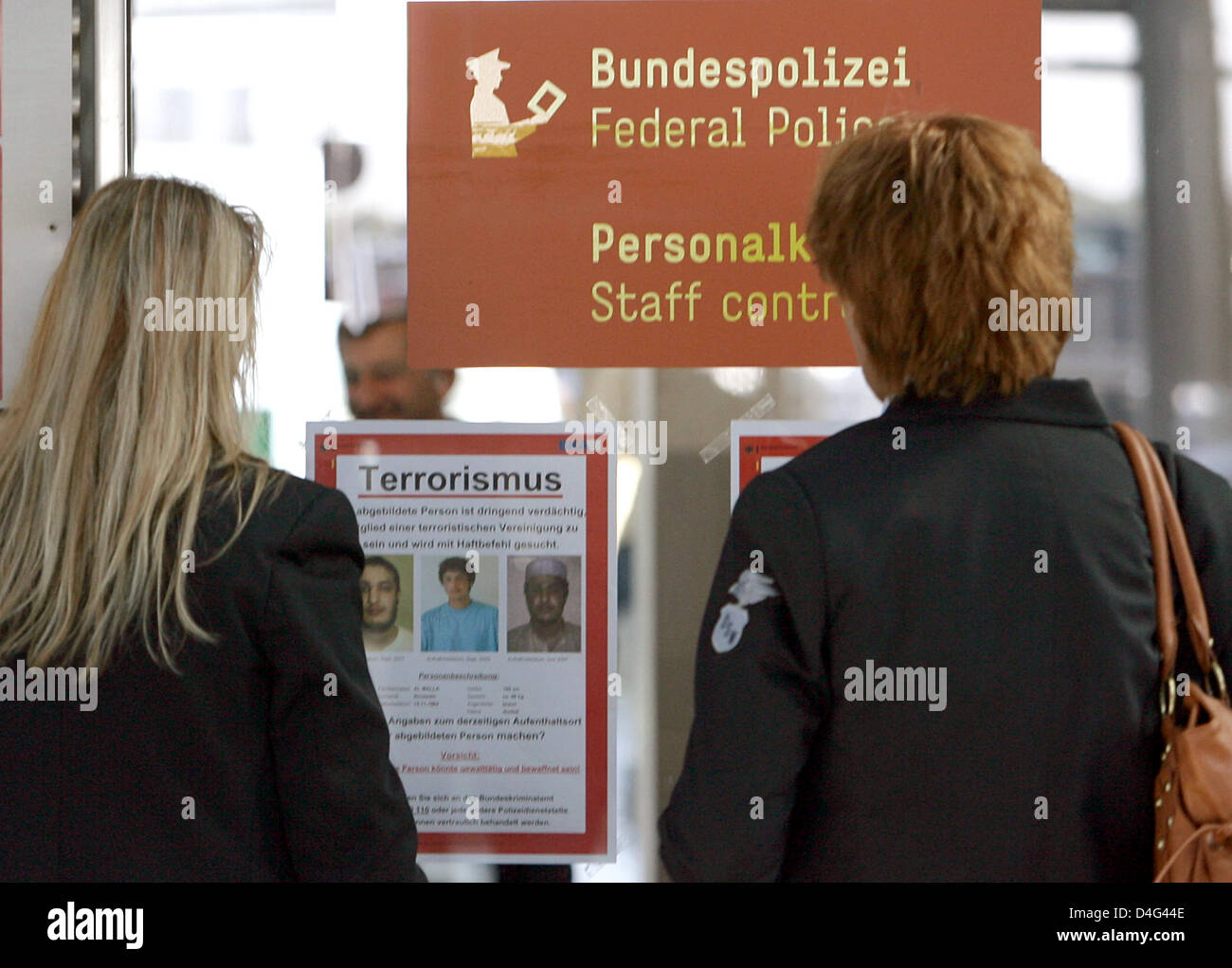Security guards look at a wanted poster showing terror suspects at ...