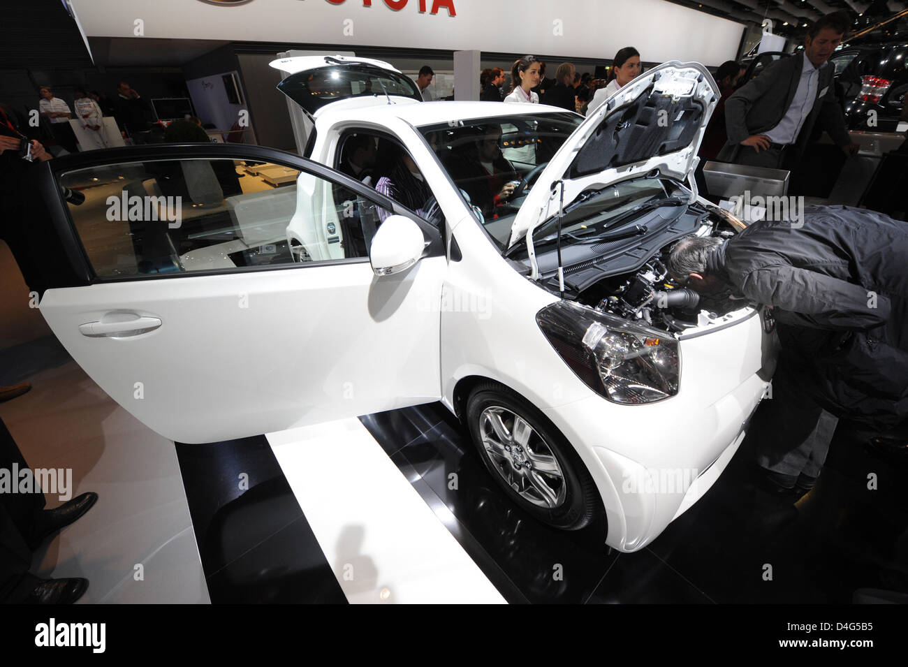 A visitor closely examines the engine compartment of a Toyota iQ68 ...