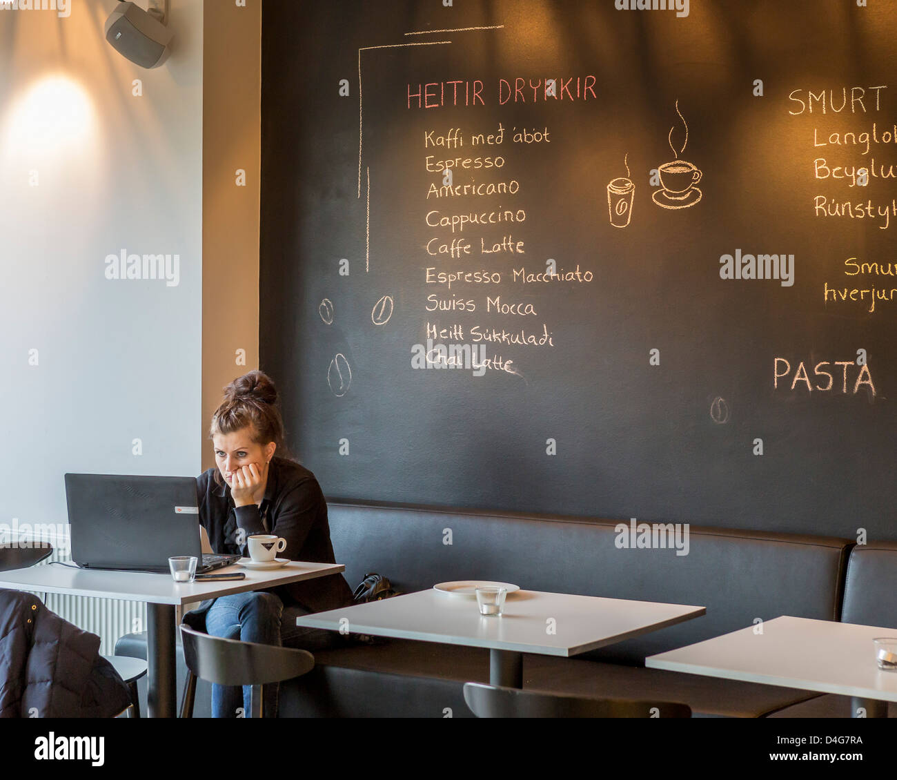 Woman using a laptop computer in a cafe in Reykjavik, Iceland Stock ...