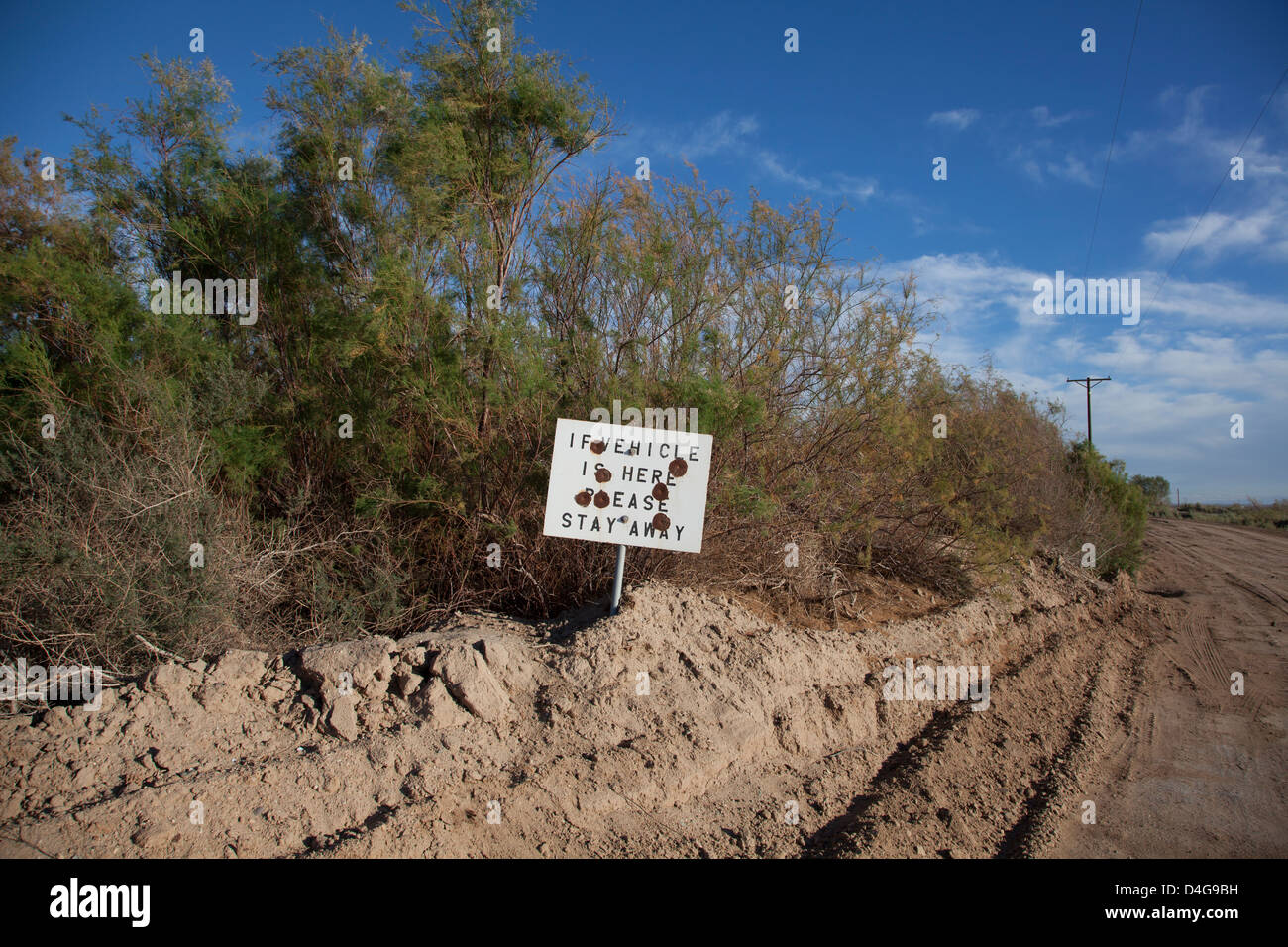 A bullet ridden sign warning of no parking at entrance to Slab City, an ...