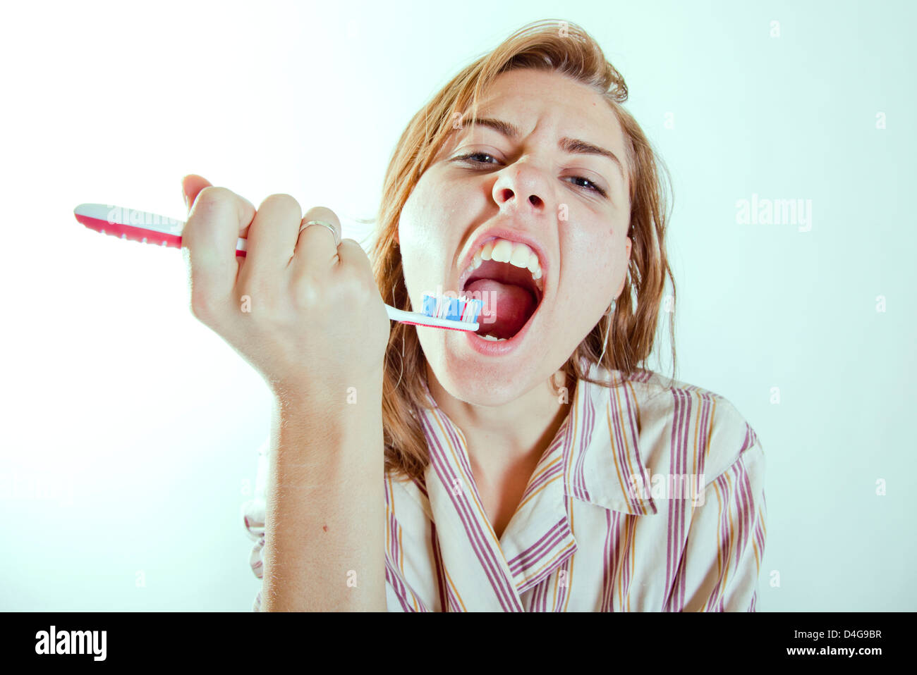 young attractive woman screaming with a tooth brush in her hands while ...