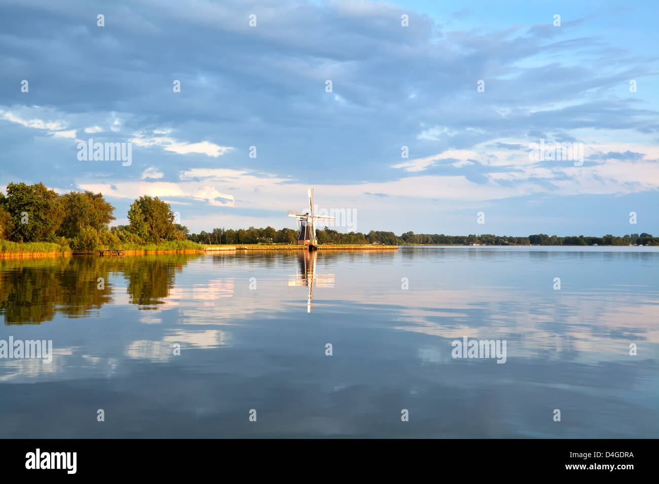 charming Dutch windmill by lake before sunset Stock Photo - Alamy