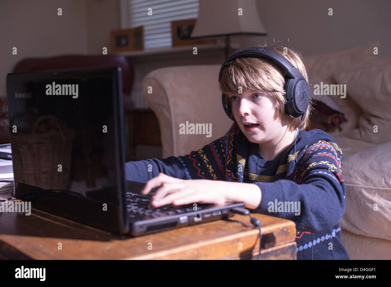 Young white boy in a living room staring at a laptop screen with ...