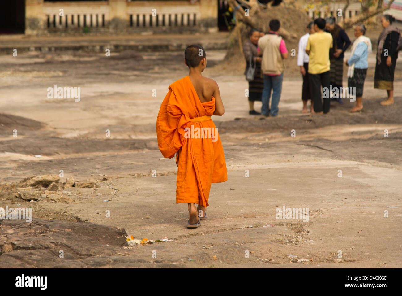A young monk in a saffron robe walks towards a group of people Stock ...