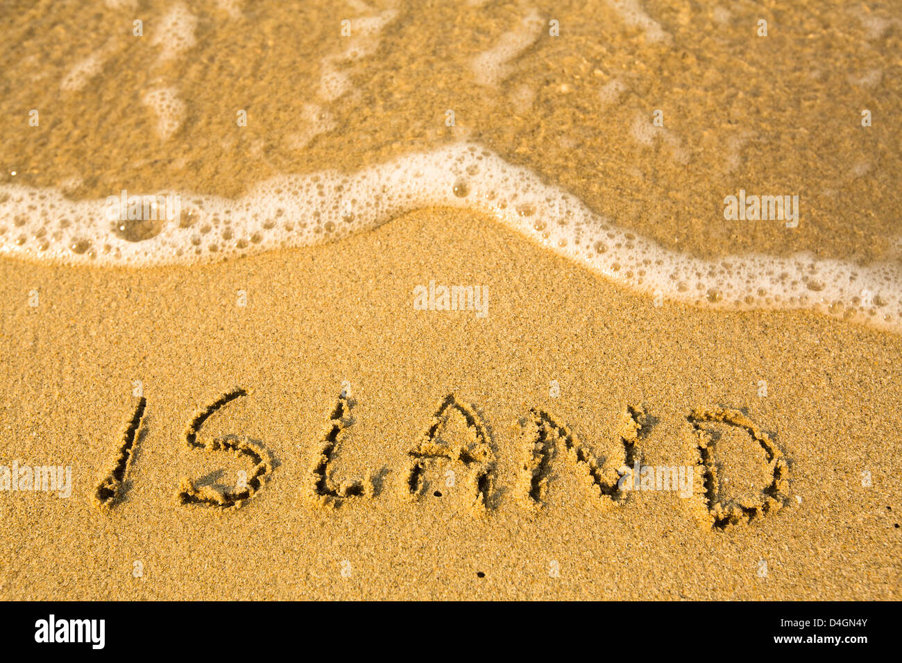 Island - written in sand on beach texture - soft wave of the sea Stock ...