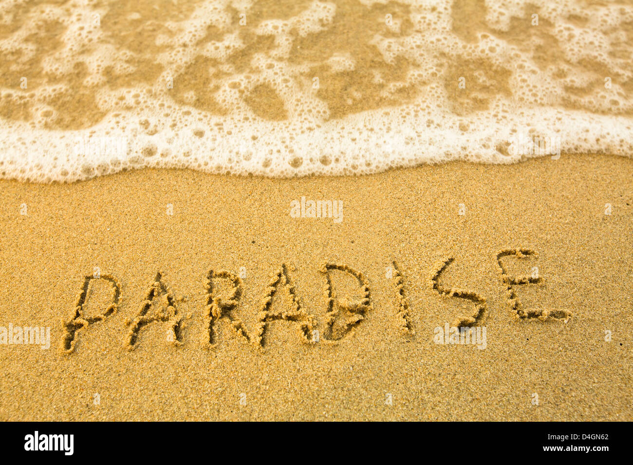 Paradise - written in sand on beach texture - soft wave of the sea ...