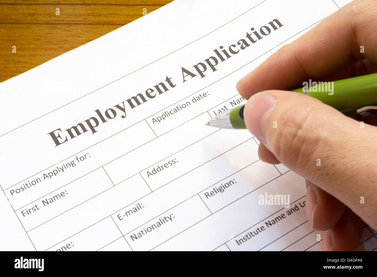man's hand with a fountain pen over blank "application for employment ...
