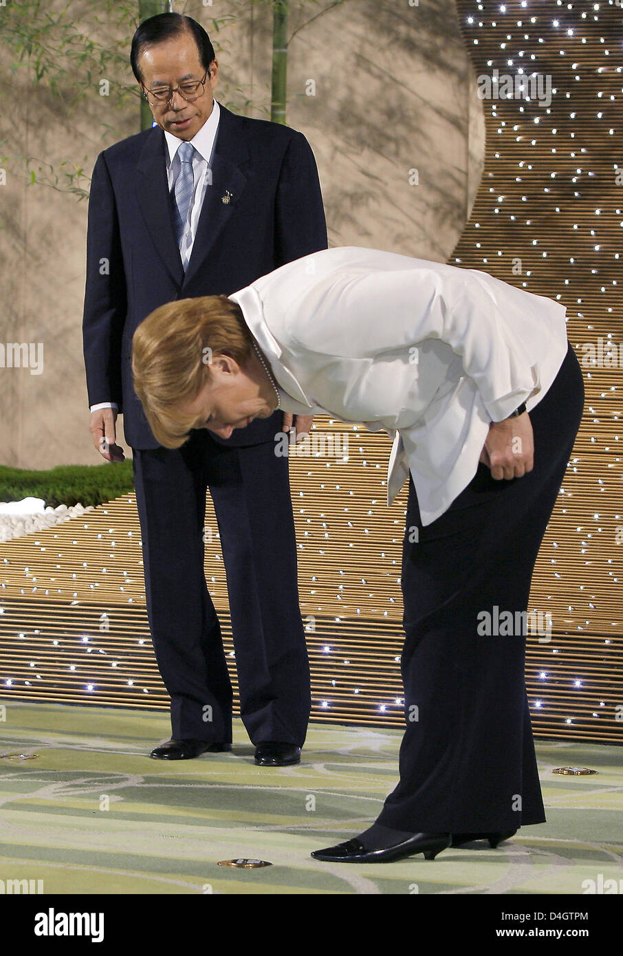 German Chancellor Angela Merkel (R) examines a power plug in the floor ...
