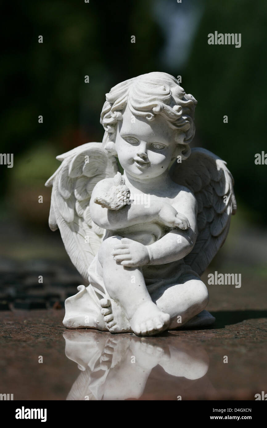 A sculpture of an angel with a bird sitting on its hand seen on a grave ...