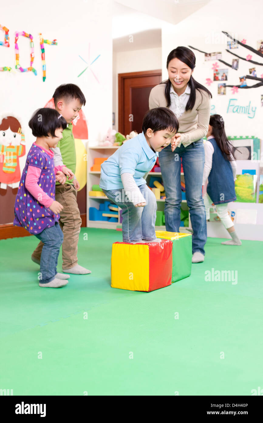 Cheerful kindergarten children playing games with teacher Stock Photo ...