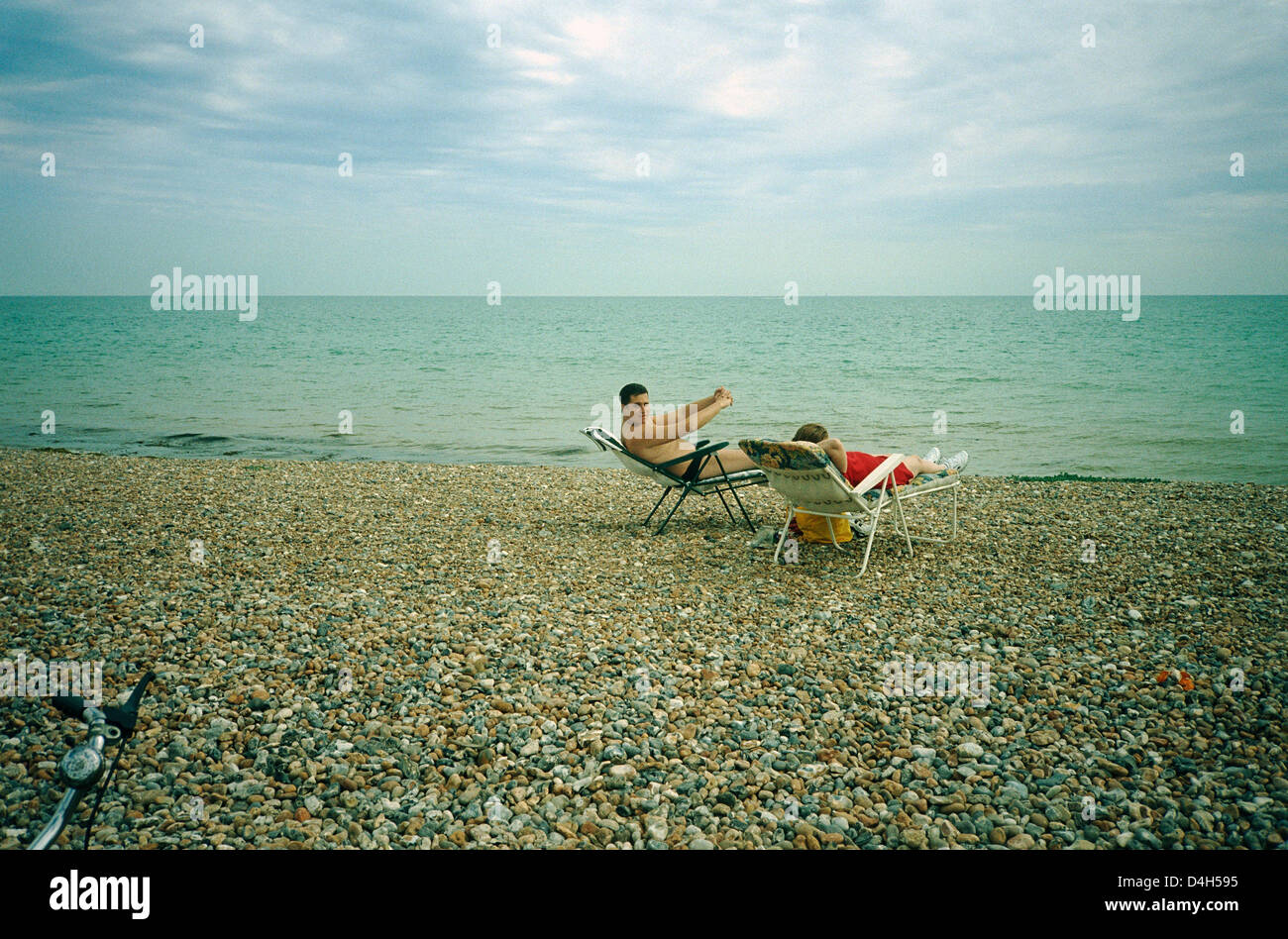 Couple sunbathing on pebble beach, Sussex, UK Stock Photo - Alamy