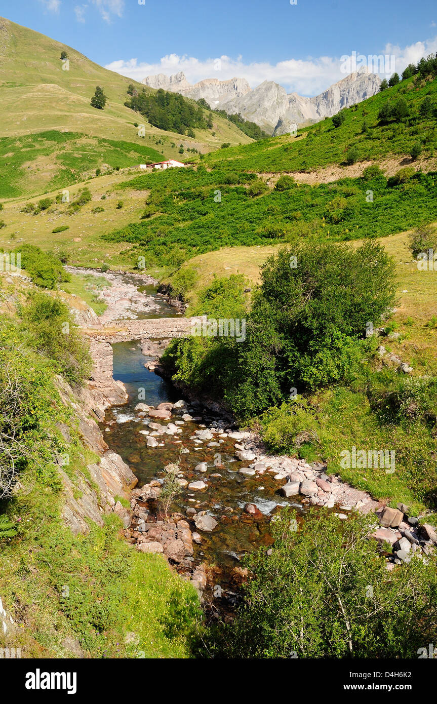 Bridge over Rio Aragon Subordan in the upper Hecho valley overlooked by ...