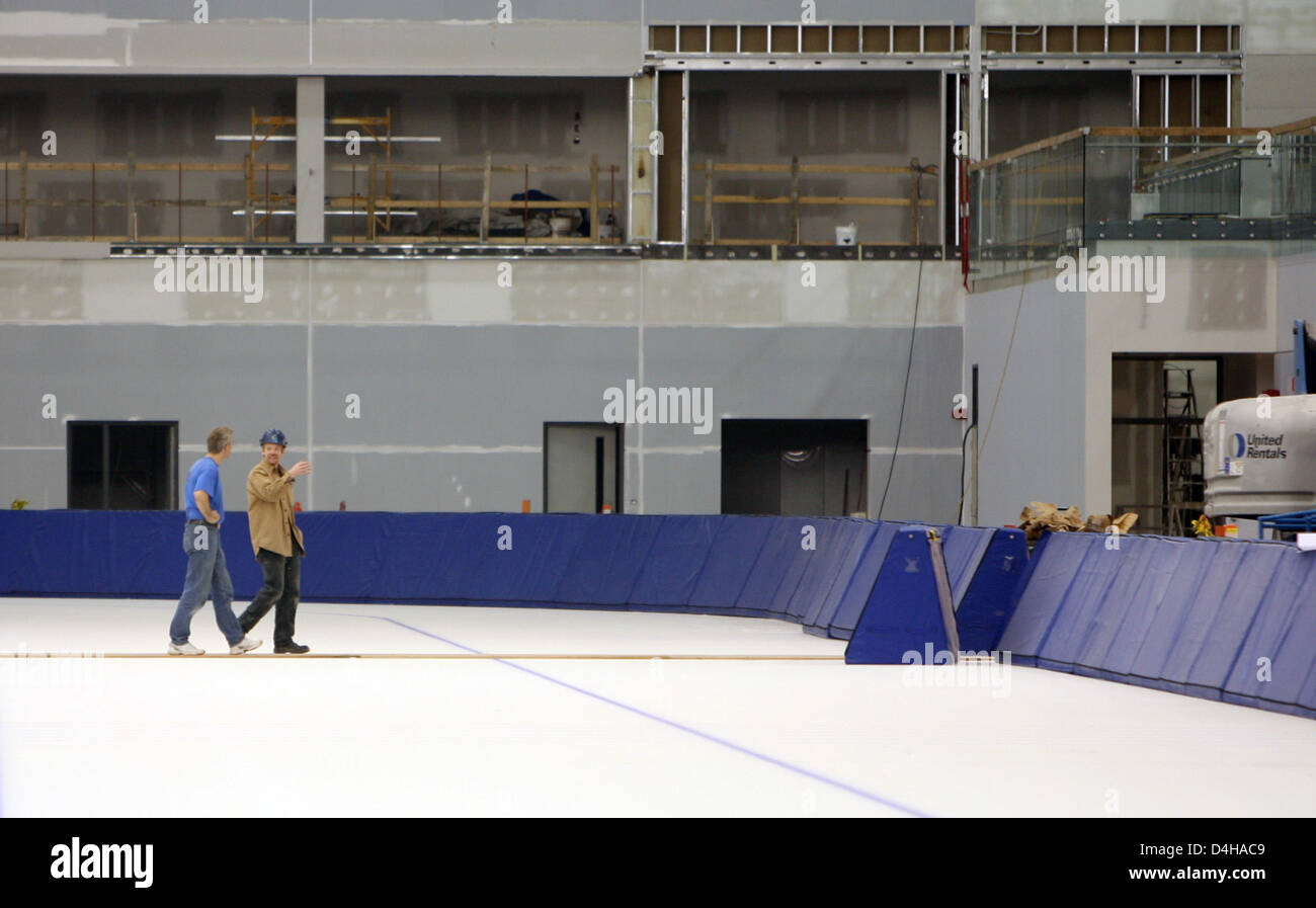 Construction workers walk across the skating rink at Richmond Olympic ...
