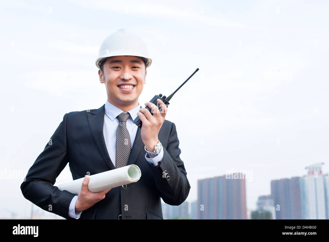 Young male architect with intercom and blueprint outdoors Stock Photo ...
