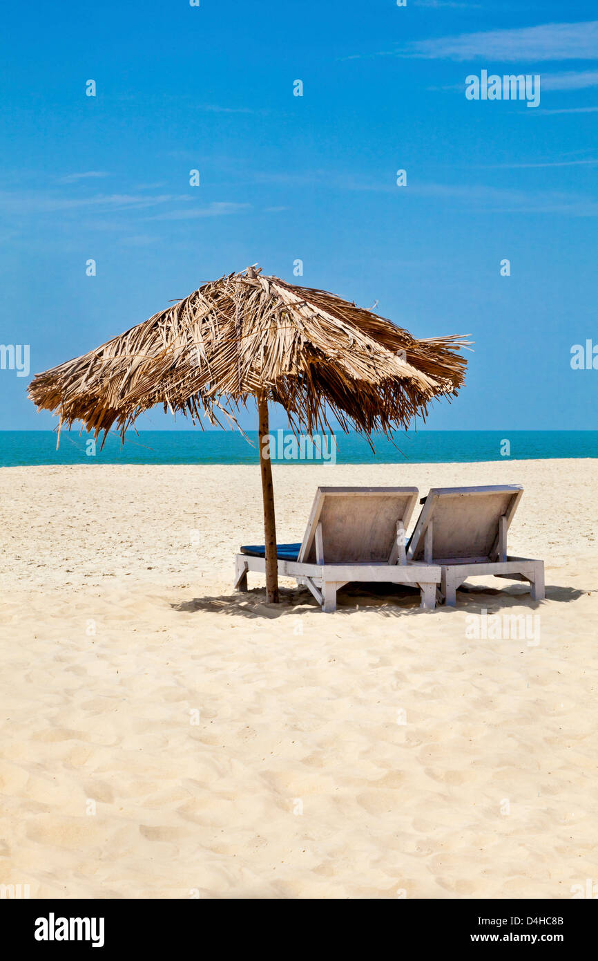 A generic vertical portrait of a tropical deserted beach with loungers ...