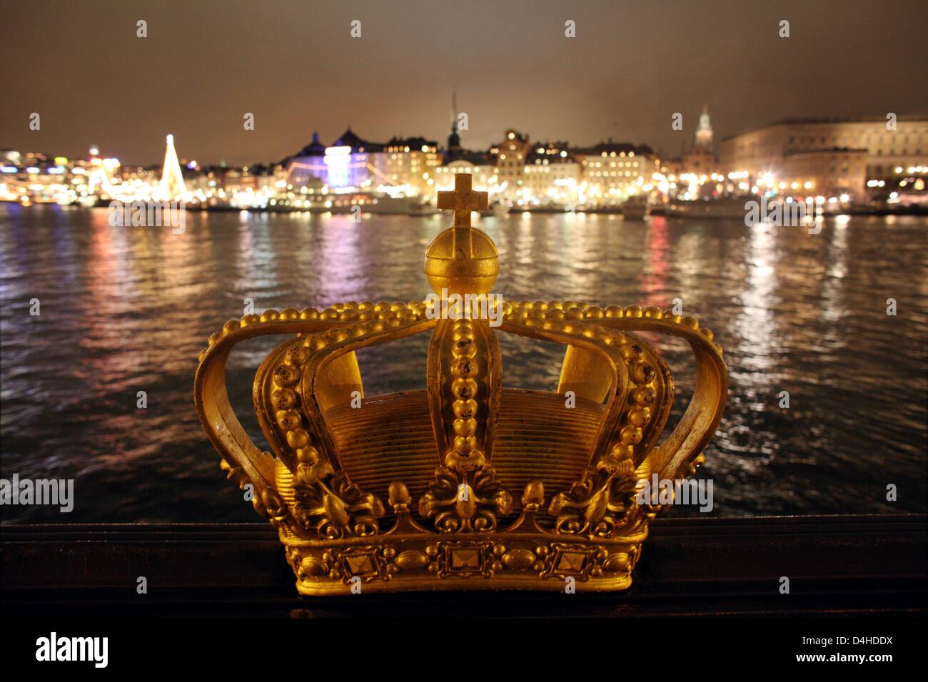 A crown decorates a bridge parapet in front of the brightly illuminated ...