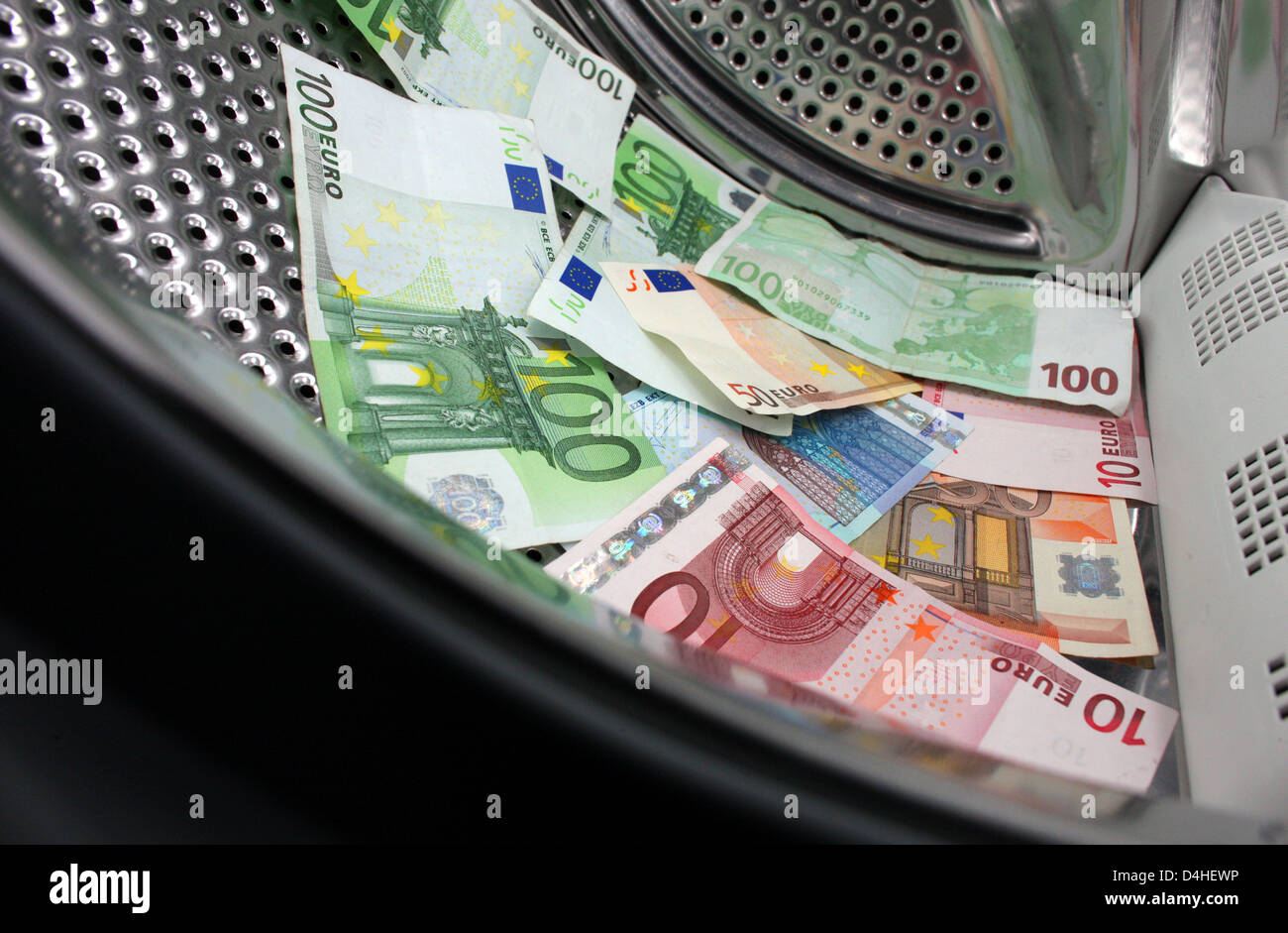 The symbolic photo shows euro notes inside a washing machine, depicted ...