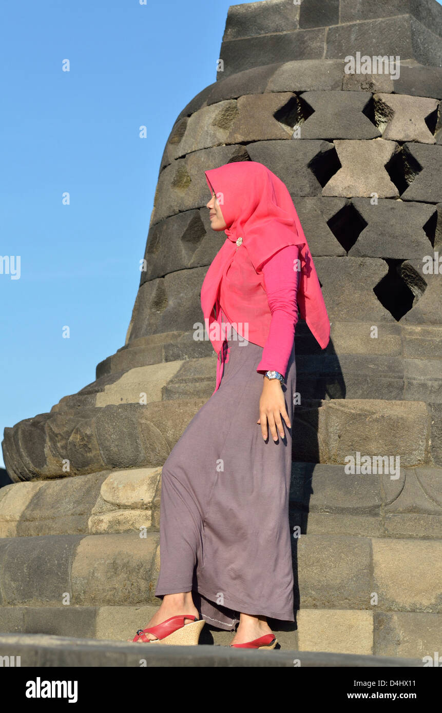 A veiled indonesian woman stands close to one of the magnificent stupa ...