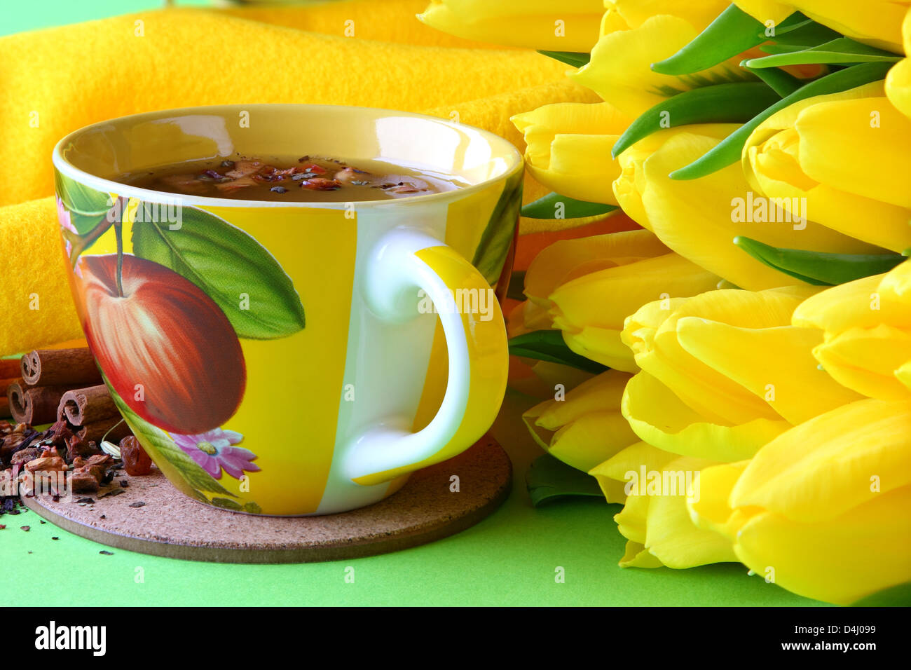 Tea cups and yellow tulips on green background Stock Photo - Alamy