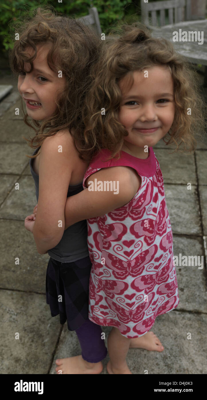 Sisters Back To Back Linking Arms In The Garden England Stock Photo - Alamy