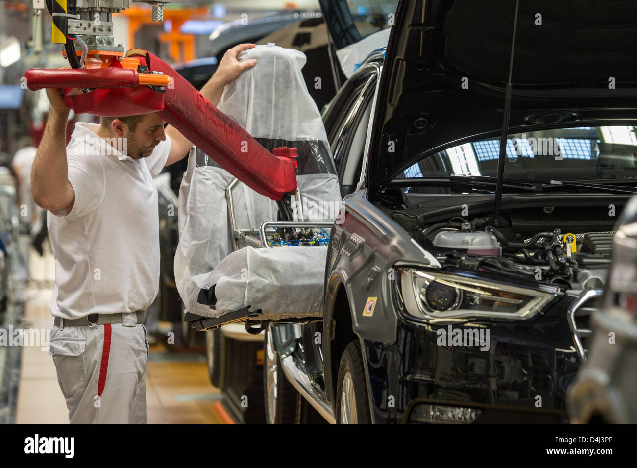 An employee of the Audi Factory lifts seat into an Audi A3 on the ...