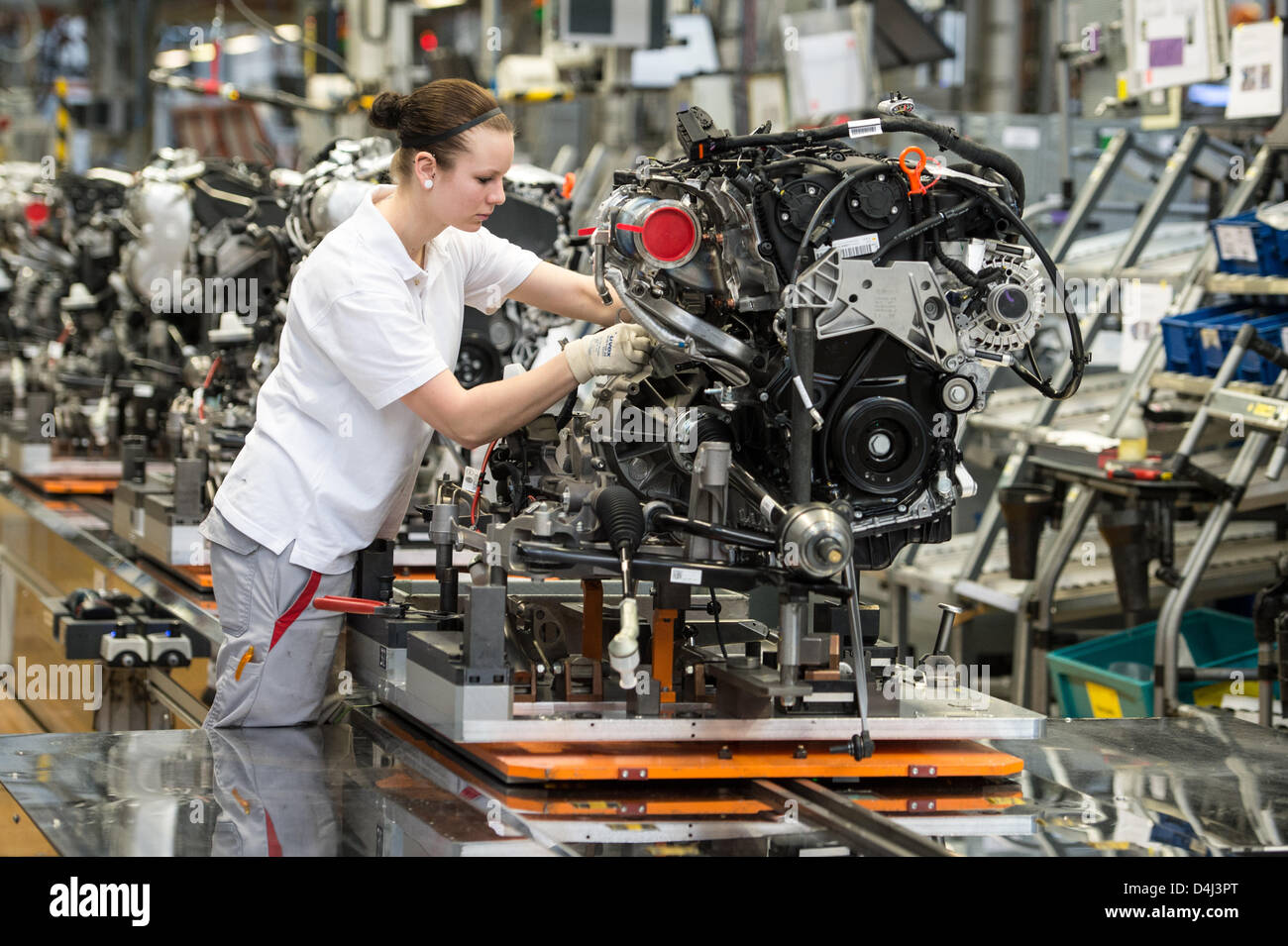An employee of the Audi Factory assembles an engine on the production ...