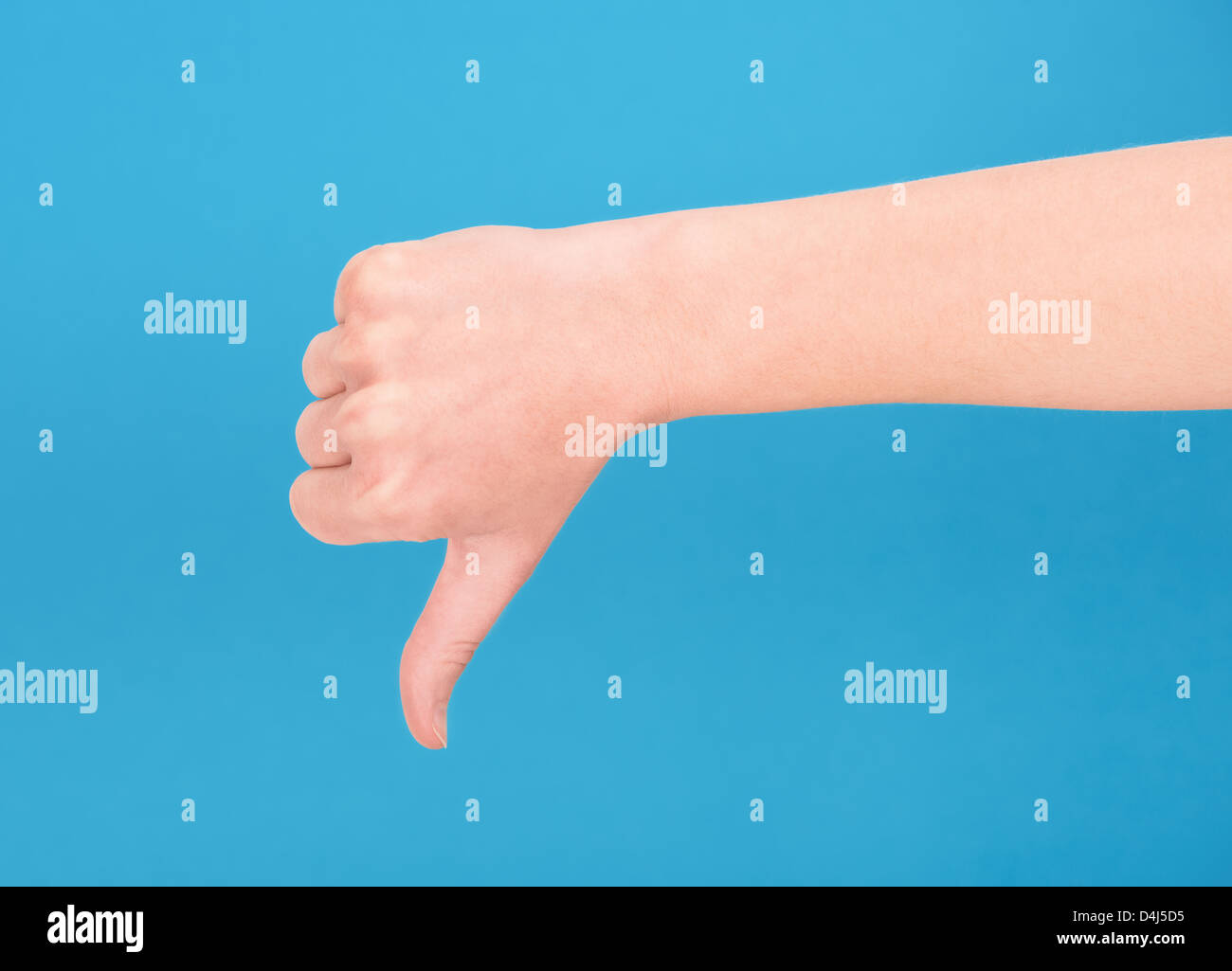 Right hand showing thumb down on blue background Stock Photo - Alamy