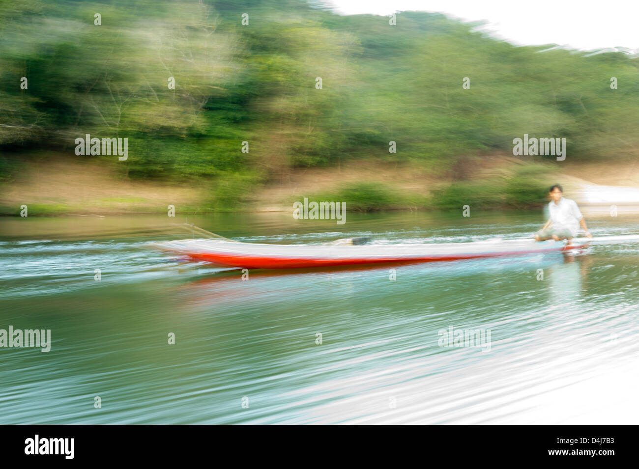 A long-tail boat speeds by in a blur Stock Photo - Alamy