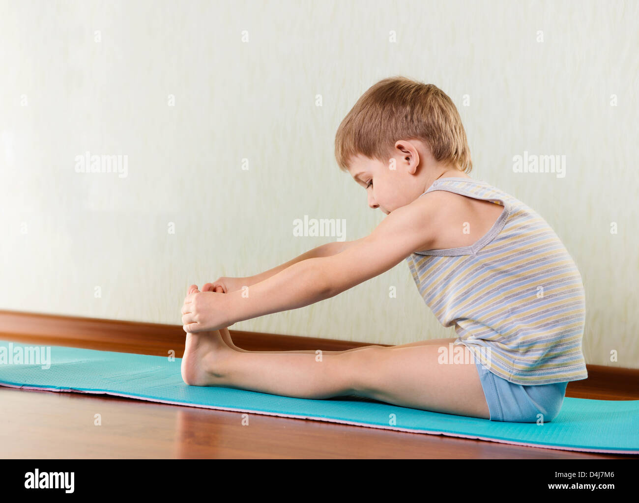 Concentrated little boy exercising and stretching in gym Stock Photo ...