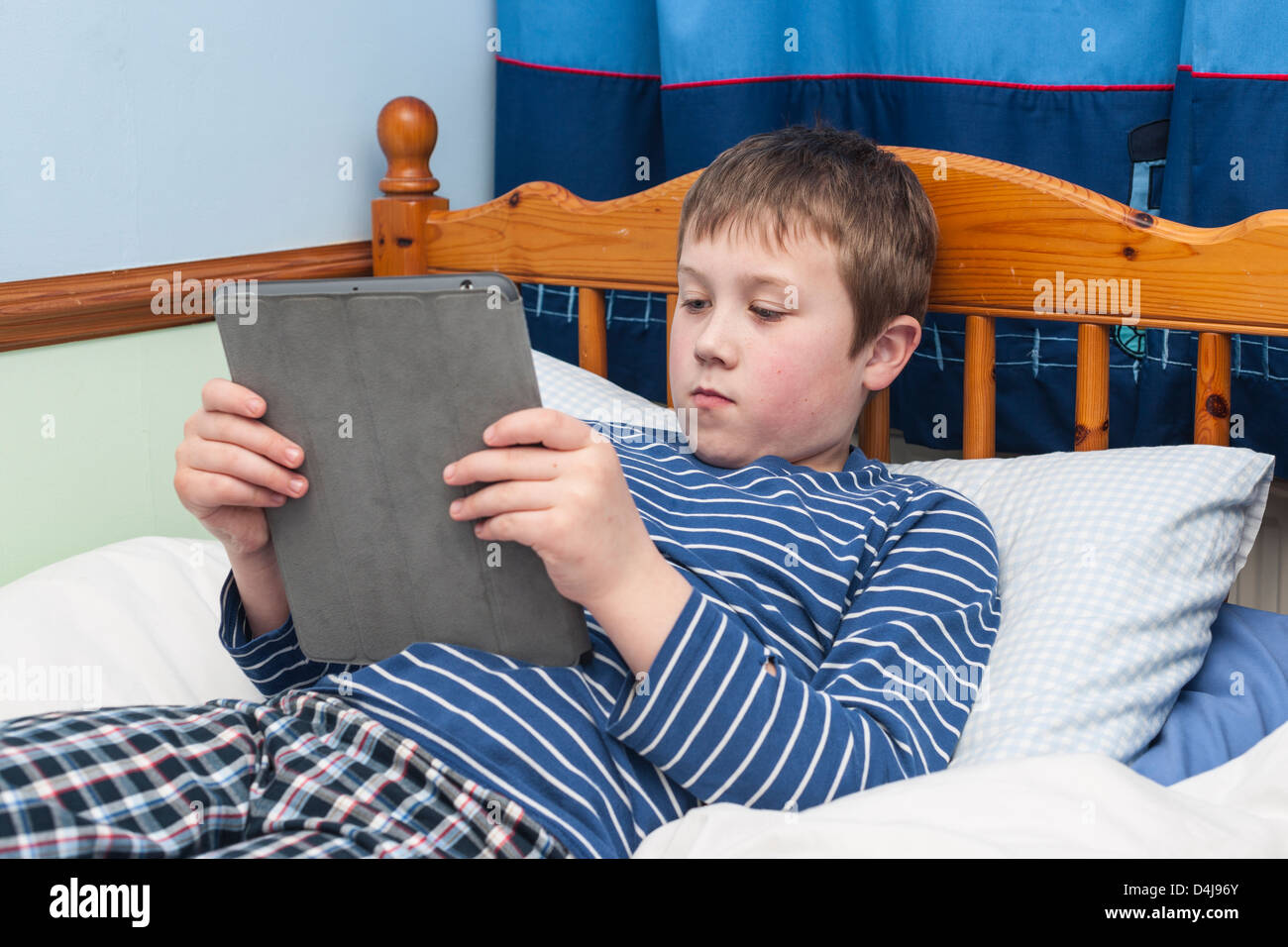 A nine year old boy using his ipad tablet in his bedroom Stock Photo ...