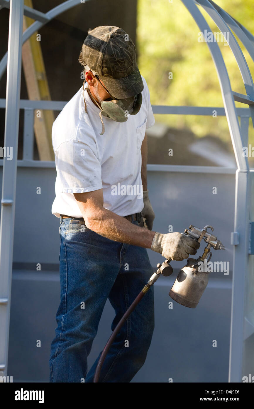 Construction steel worker uses a paint sprayer to apply a primer coat ...