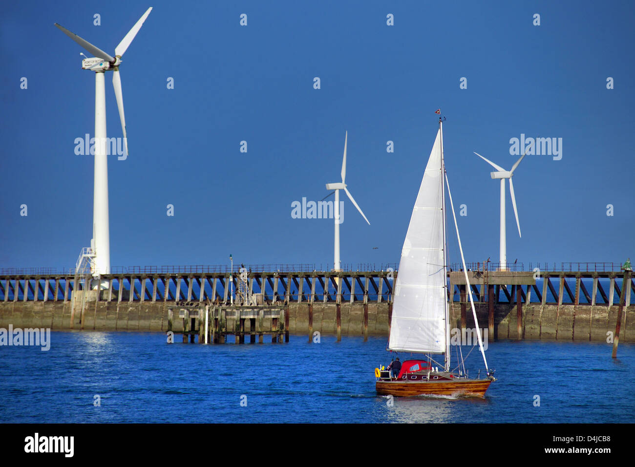 Blue Yacht passing wind turbine, Blyth Harbour, Northumberland Stock ...