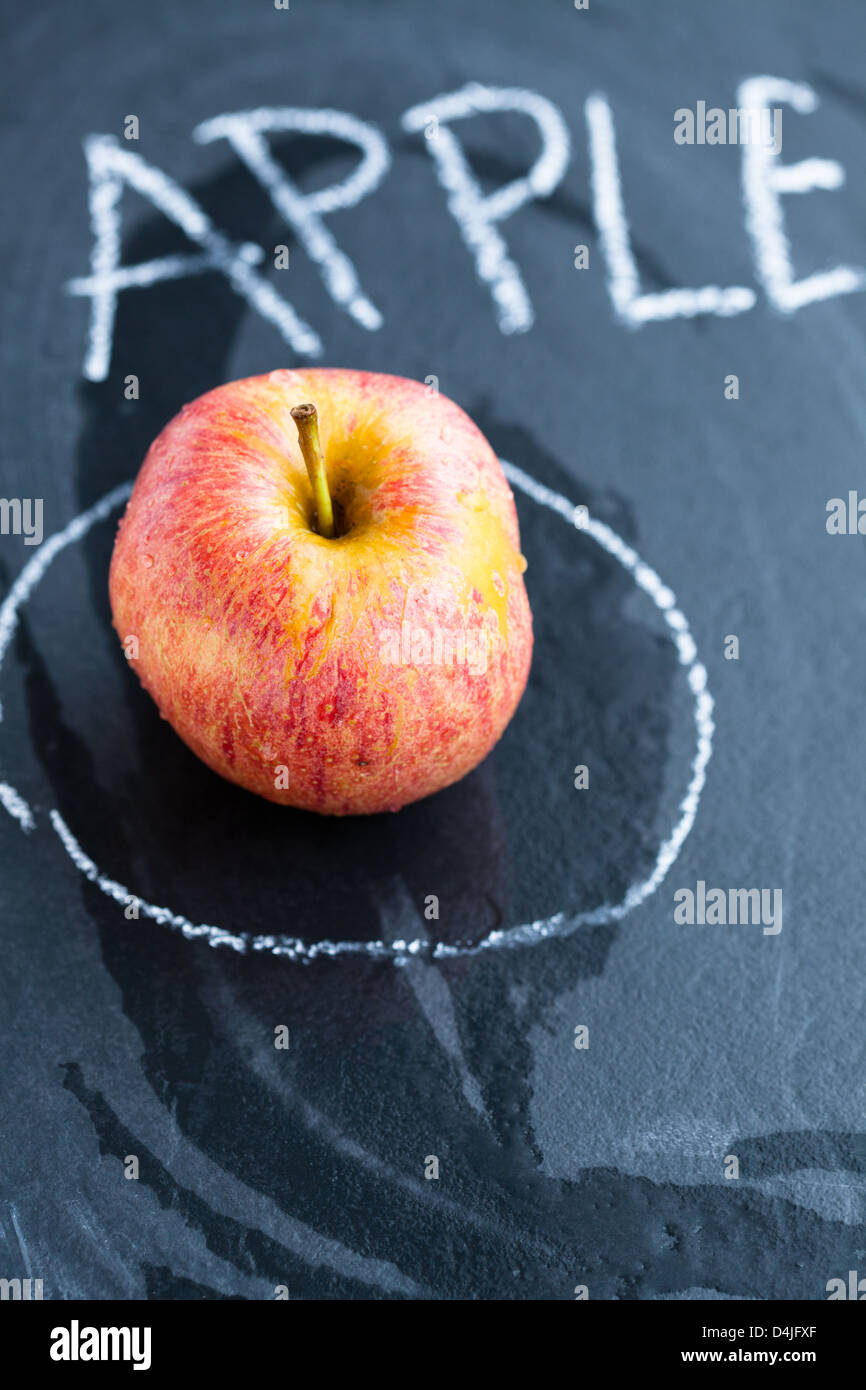 Juicy apple in circle and word apple written in chalk on dark ...