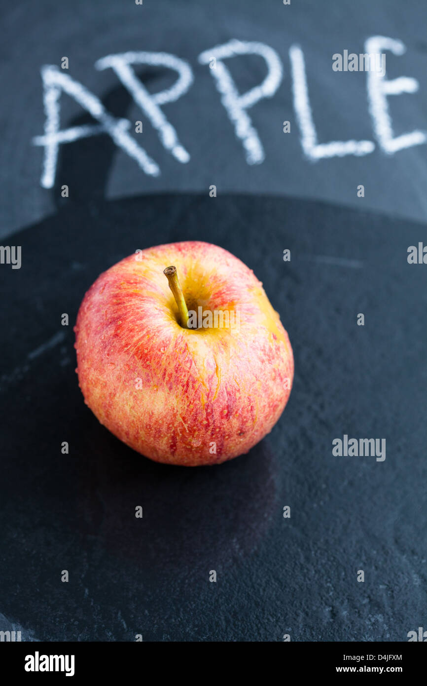 Juicy apple and word apple written in chalk on wet dark background ...