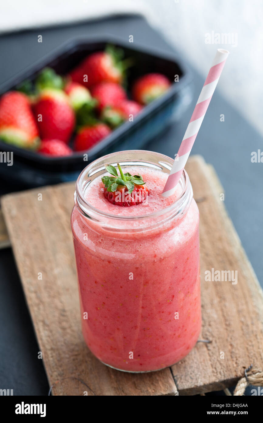 Closeup of strawberry fruit smoothie and tray of fresh strawberries in ...