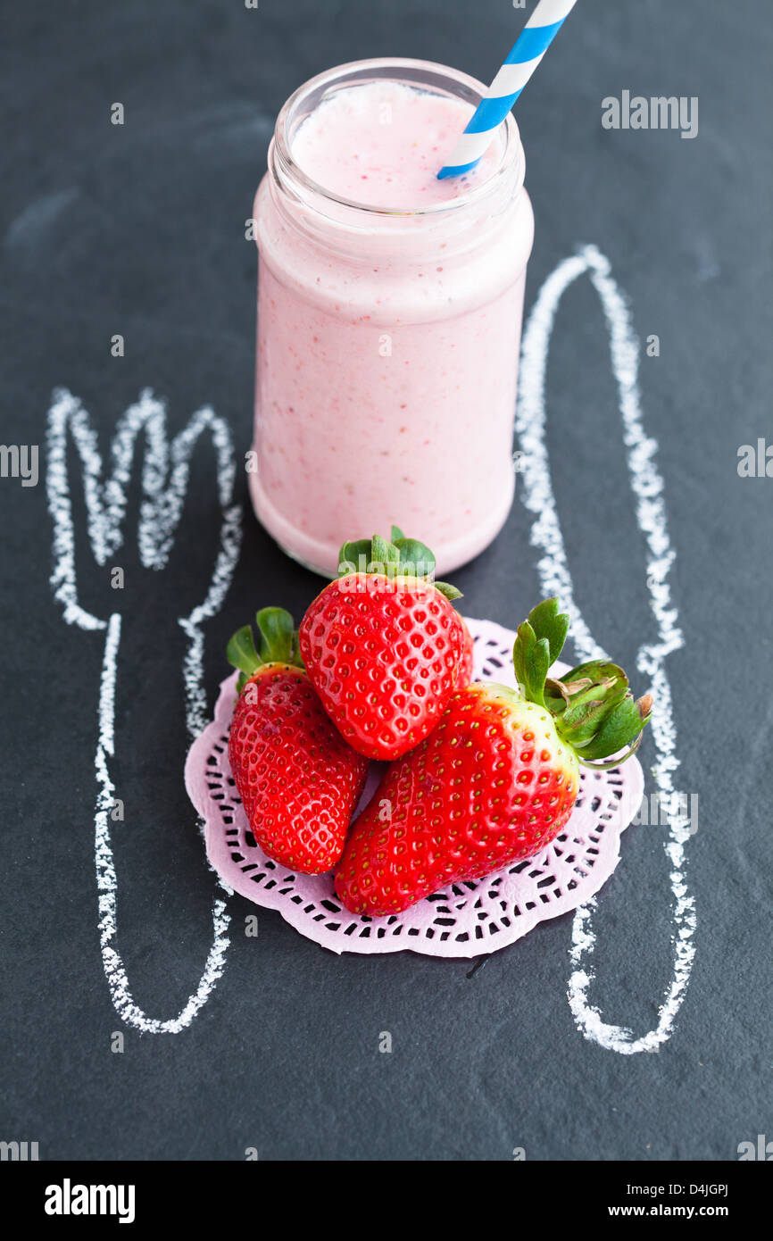 Strawberry smoothie with striped straw and whole strawberries with ...