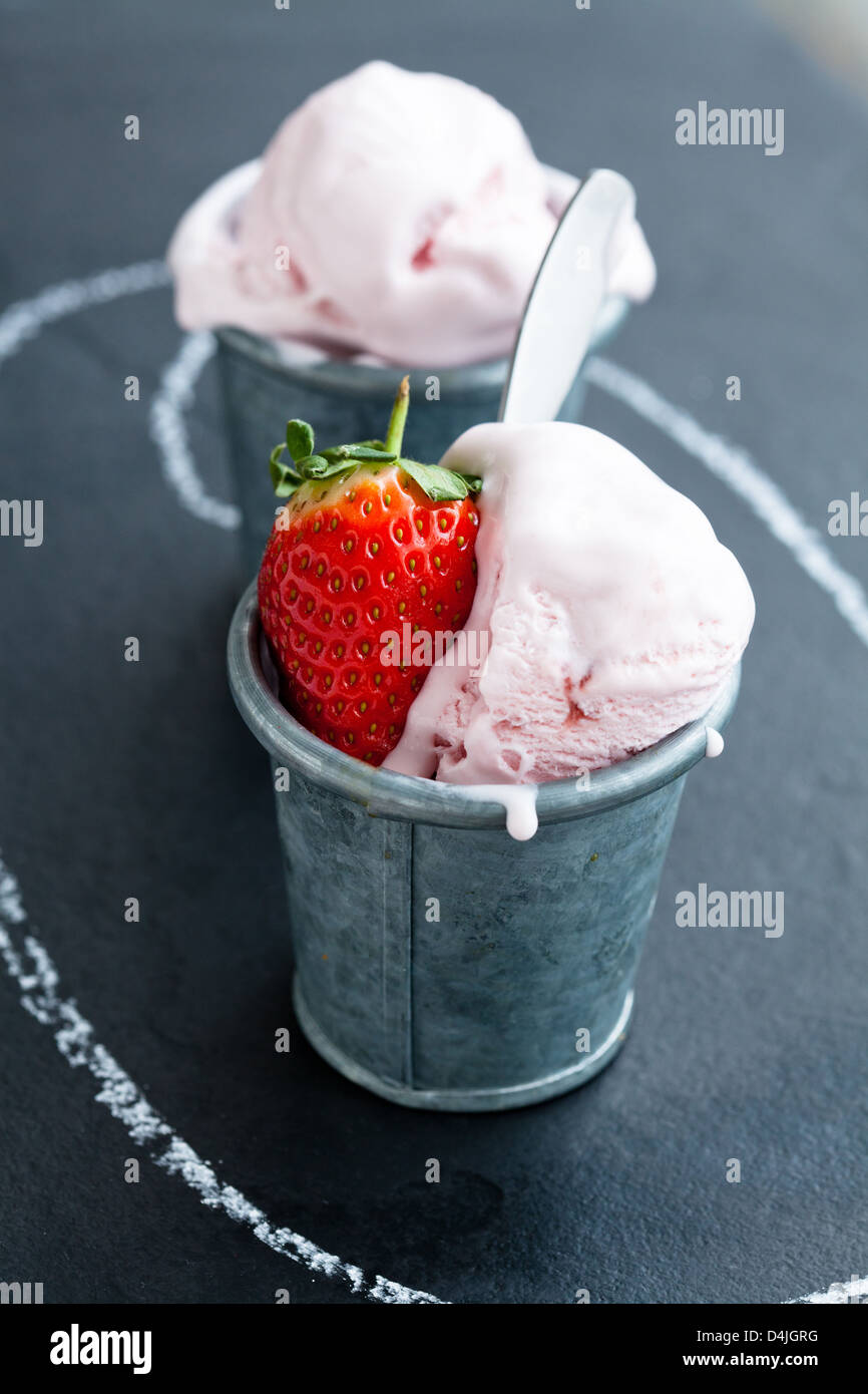 Closeup of strawberry ice cream and strawberry in two metal cups inside ...
