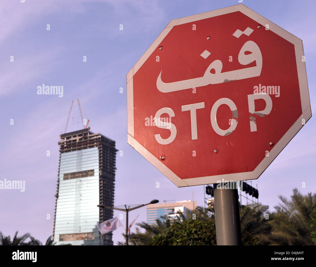The picture shows a stop sign in front of a high rise construction site ...