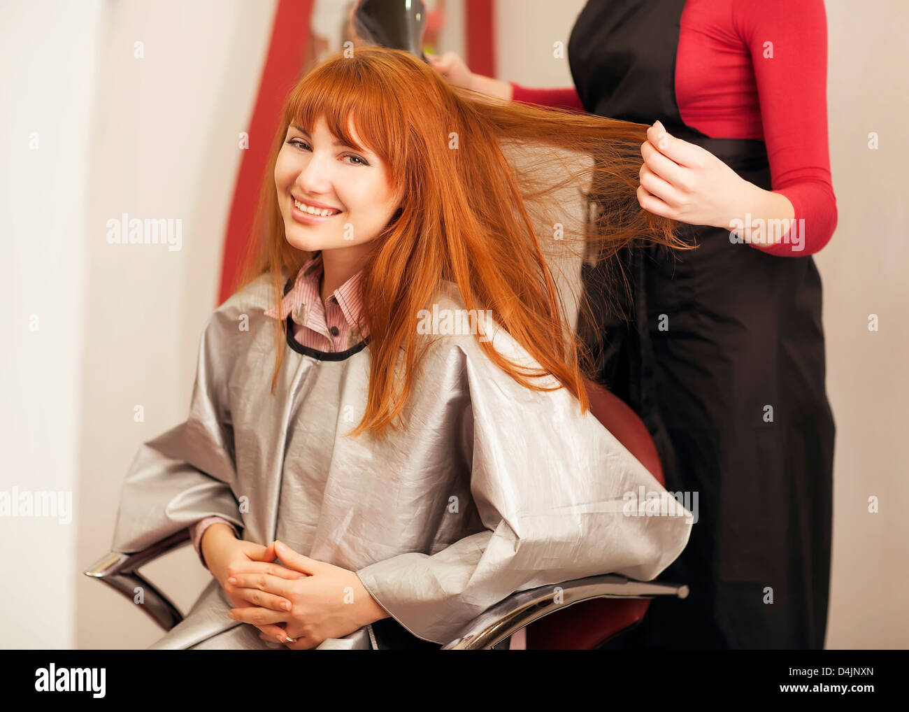 Cute young woman having her hair trimmed by a stylist Stock Photo - Alamy