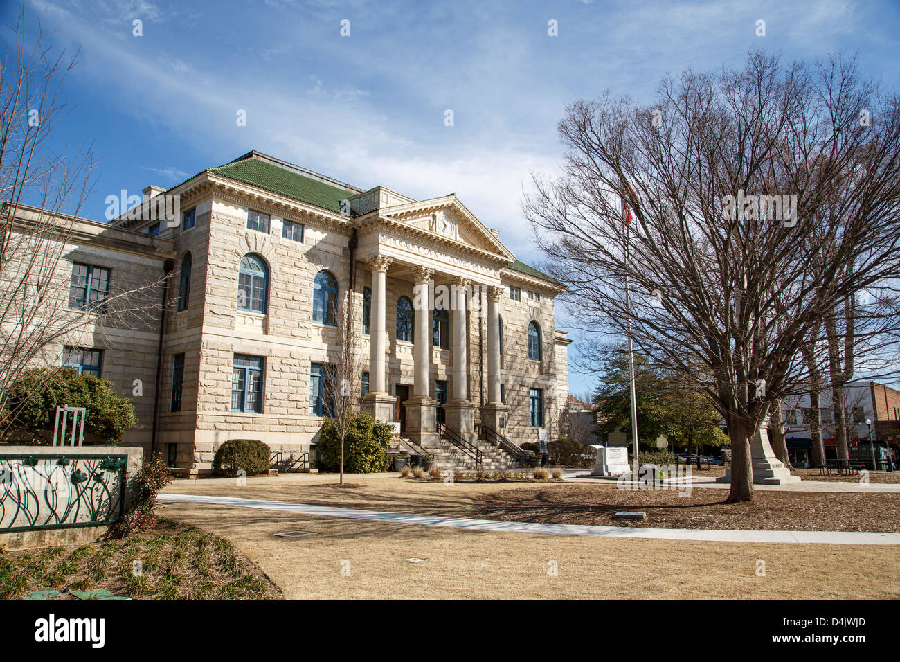 An old stone courthouse with columns in a town square under a nice sky ...
